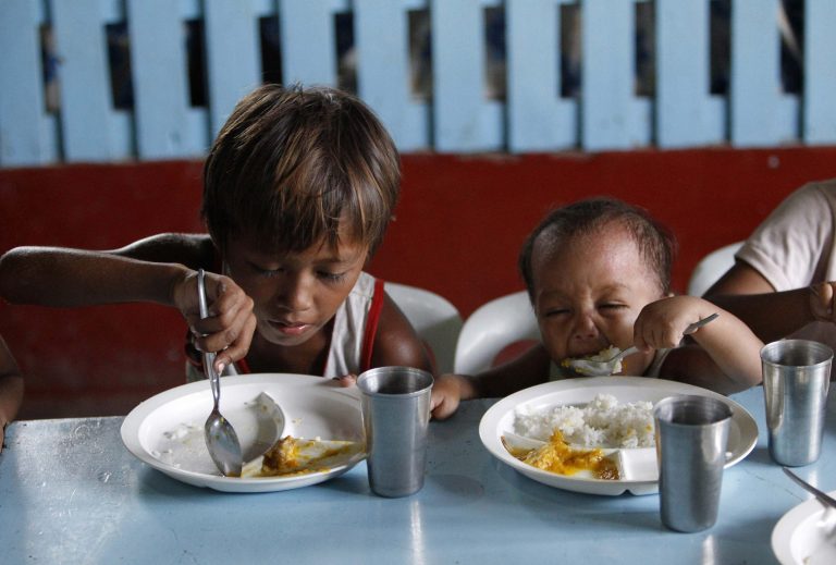 Siblings eat free meals during feeding program at a slum area in Manila ...