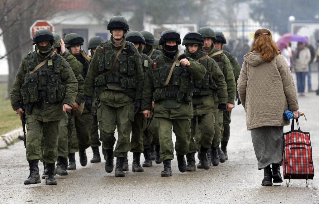 Uniformed men, believed to be Russian servicemen, walk in formation ...